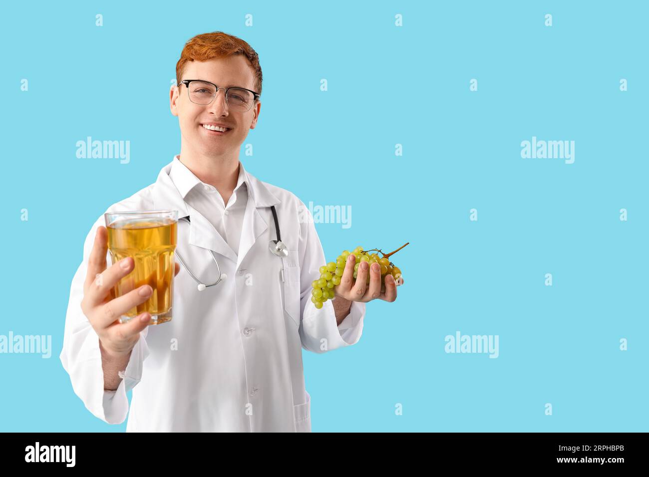 Male doctor with glass of juice and grape on blue background Stock ...