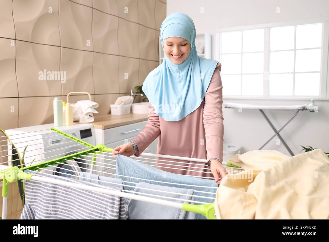 Young Muslim woman drying clothes in laundry room Stock Photo - Alamy