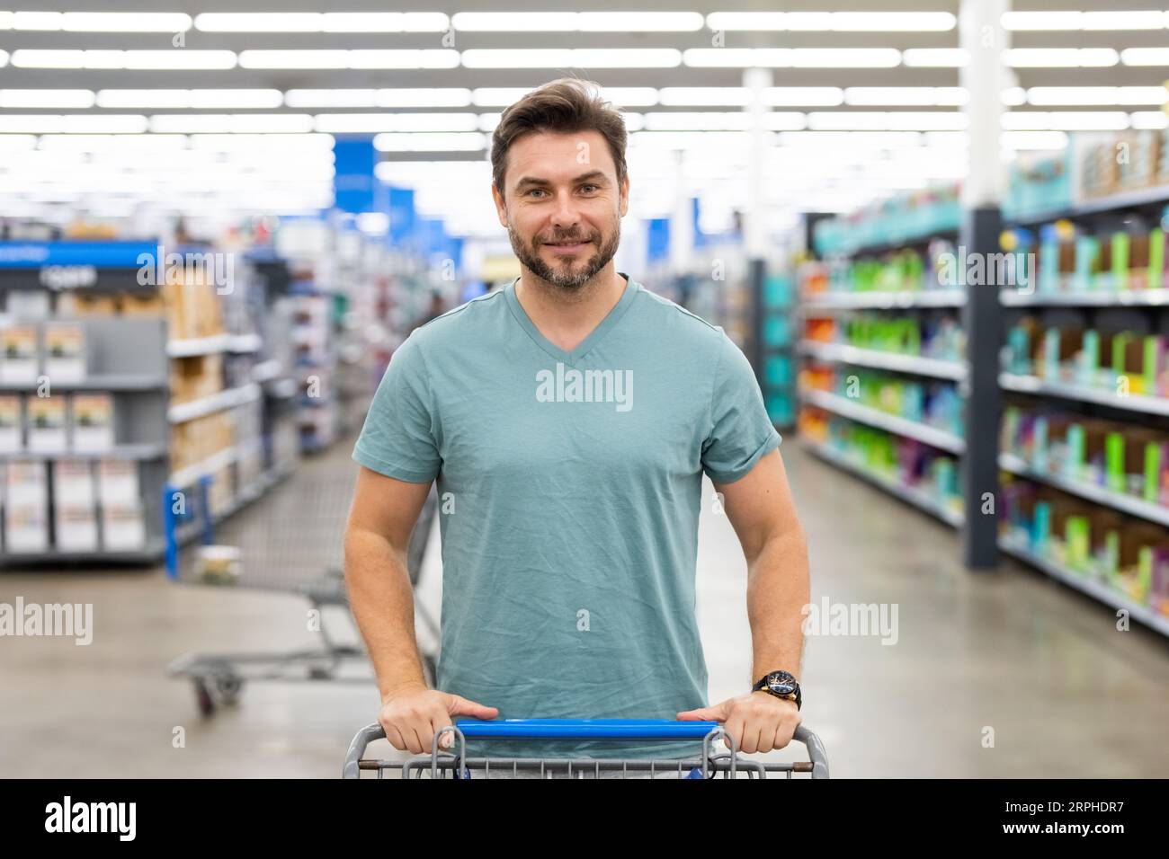 Portrait of man with shopping cart in a store. Supermarket shopping and ...