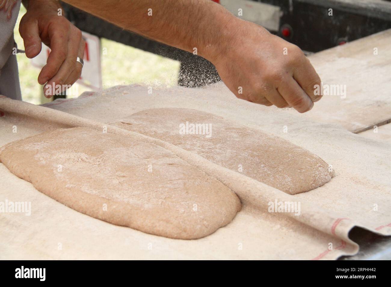 Baker powdering the raw bread loaves with flour before the baking ...