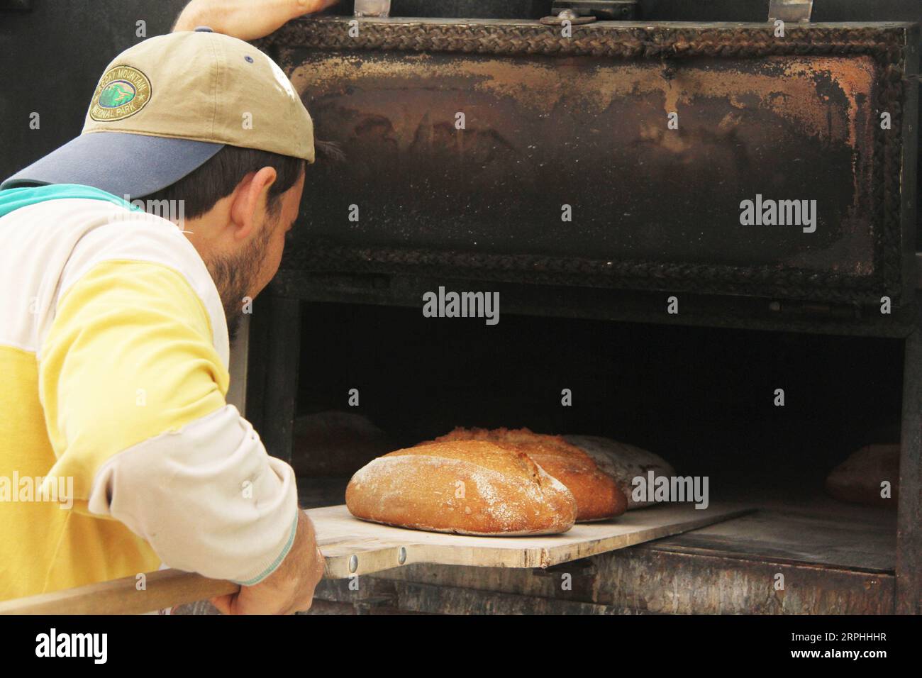 Baker taking fresh loaves of bread out of the oven Stock Photo - Alamy