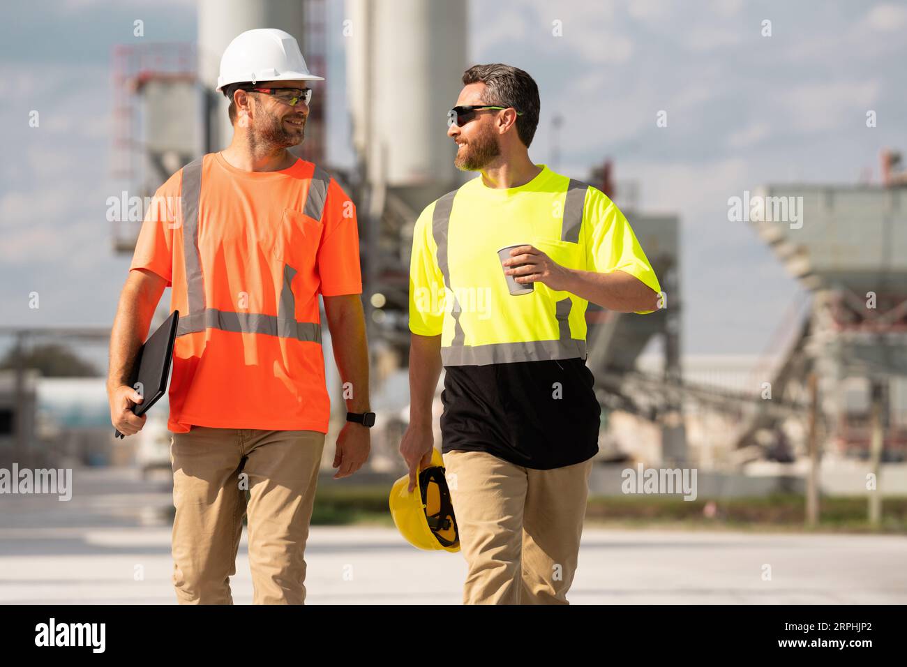 Industrial workers outdoors. Engineers in safety uniform and helmet on ...