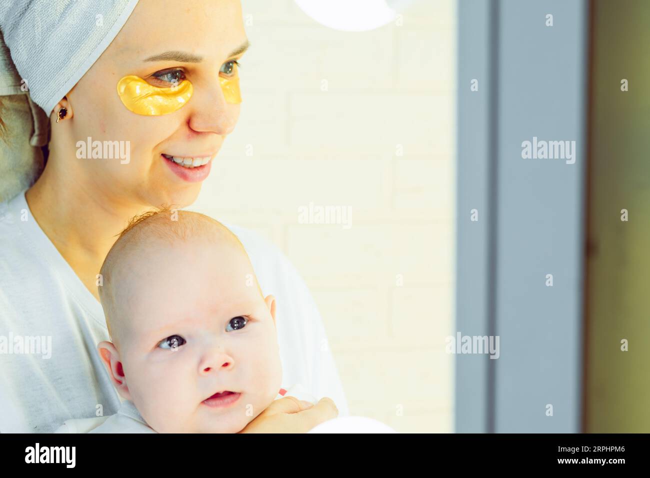 Young mother take care of her skin with under eye patches holding her ...