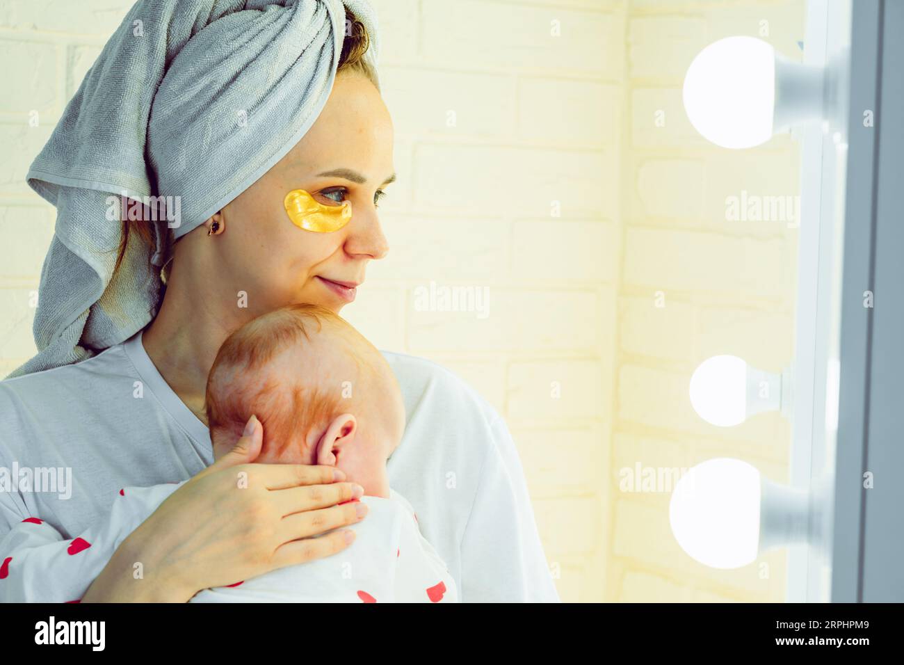 Young mother take care of her skin with under eye patches holding her ...