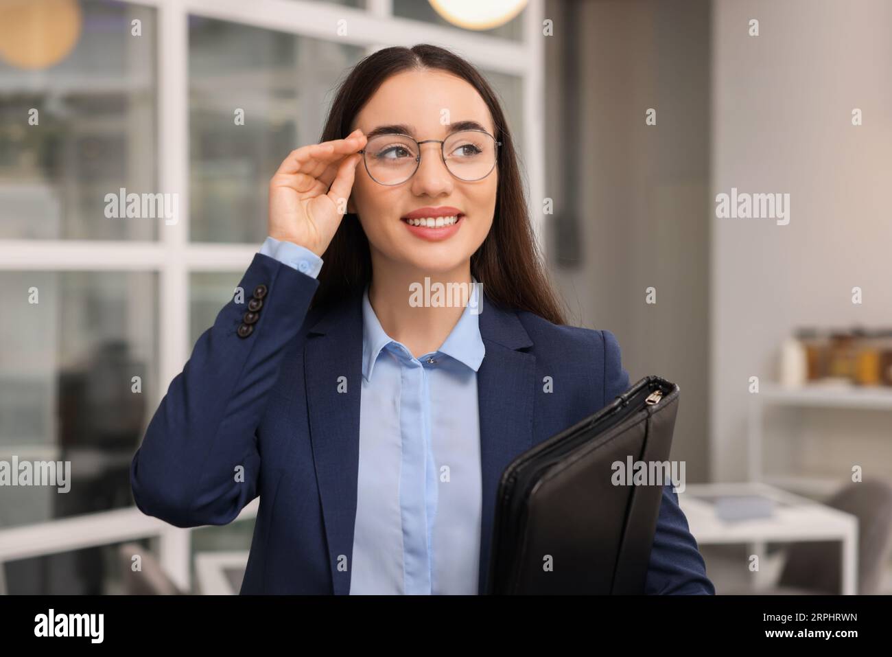 Happy real estate agent with leather portfolio in office Stock Photo ...