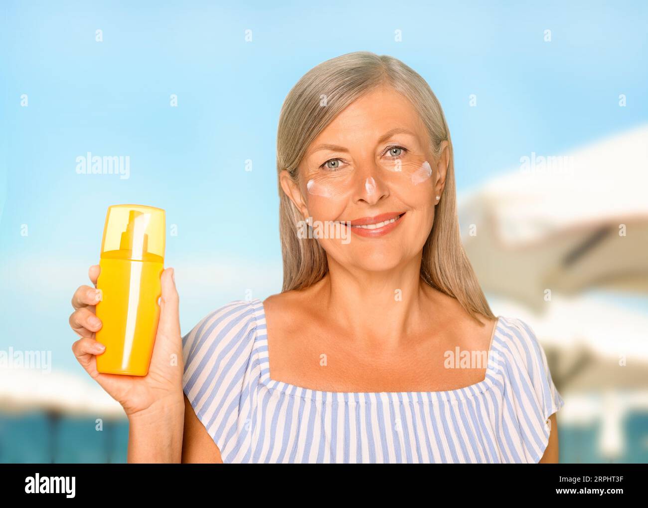 Sun protection. Beautiful mature woman with bottle of sunblock on beach ...