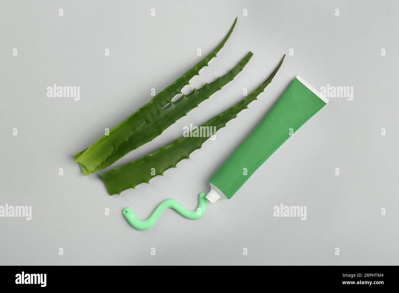 Tube of toothpaste and fresh aloe on light grey background, flat lay ...