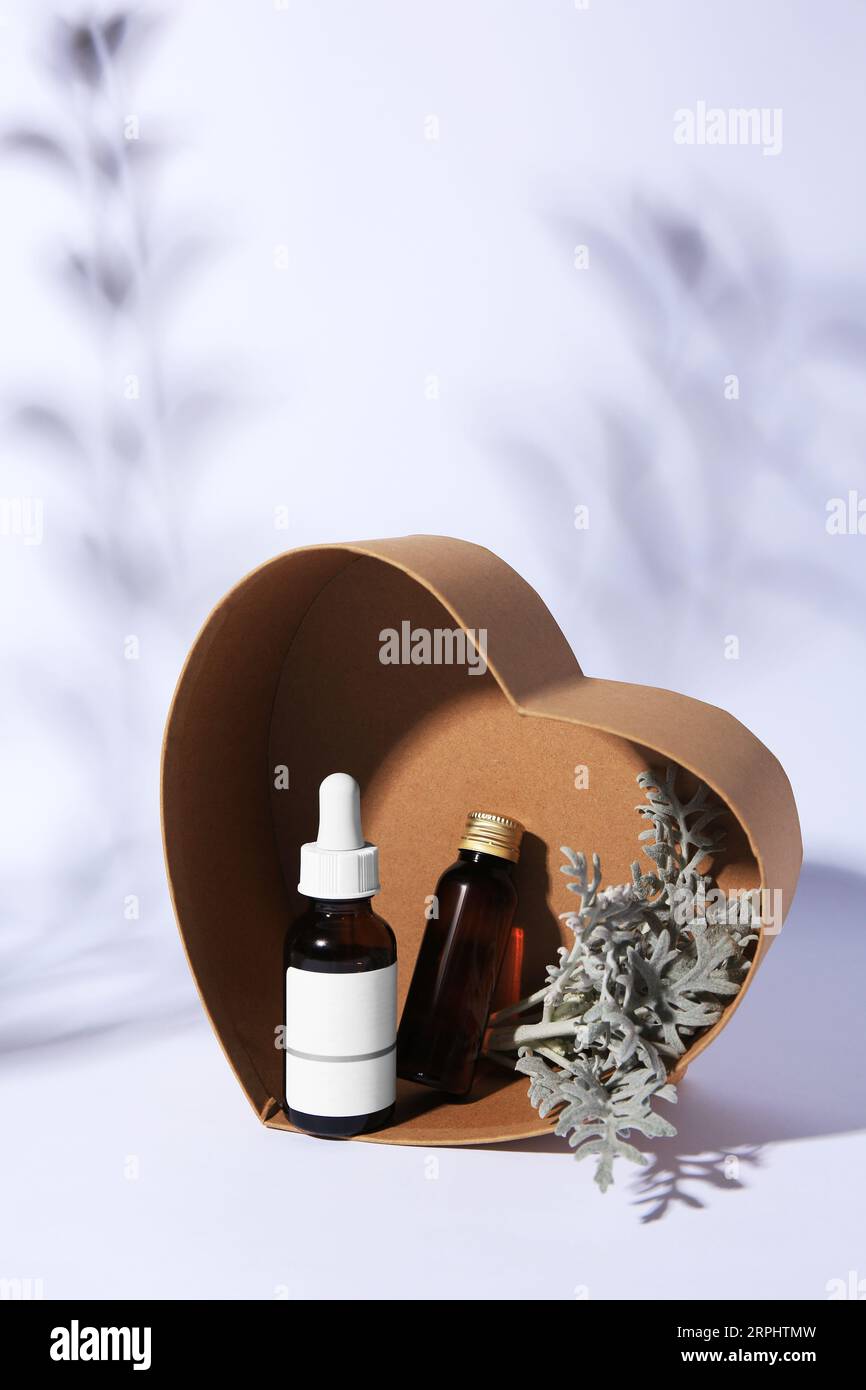 Heart shaped box with cosmetic products and silver leaves on white ...