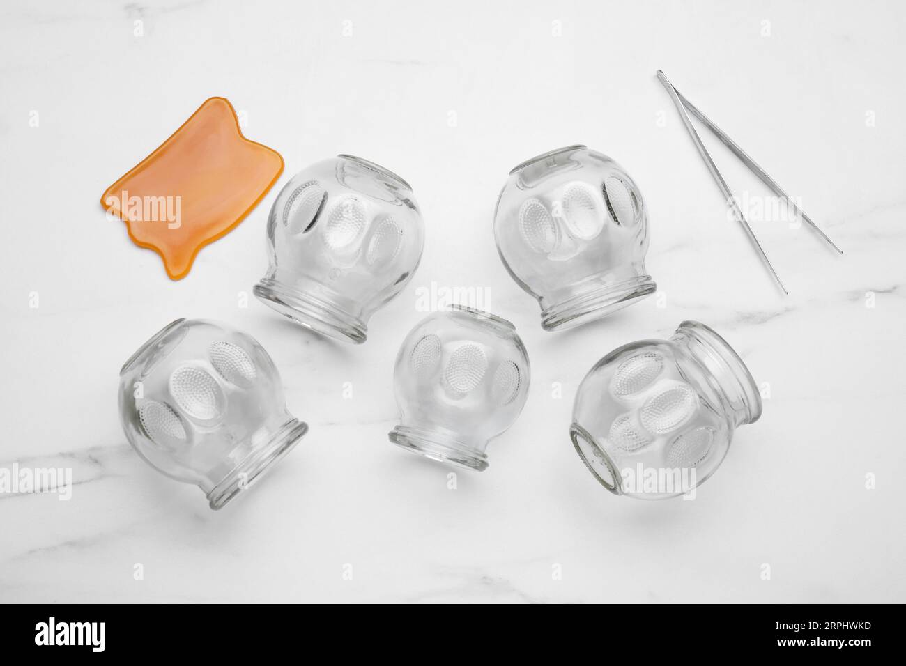 Glass cups, gua sha and tweezers on white marble table, flat lay ...