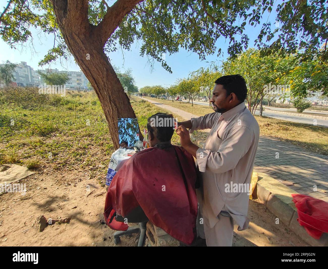 191209 -- ISLAMABAD, Dec. 9, 2019 -- A roadside barber cuts hair of his ...