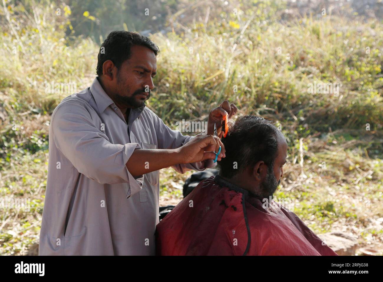 191209 -- ISLAMABAD, Dec. 9, 2019 -- A roadside barber cuts hair of his ...