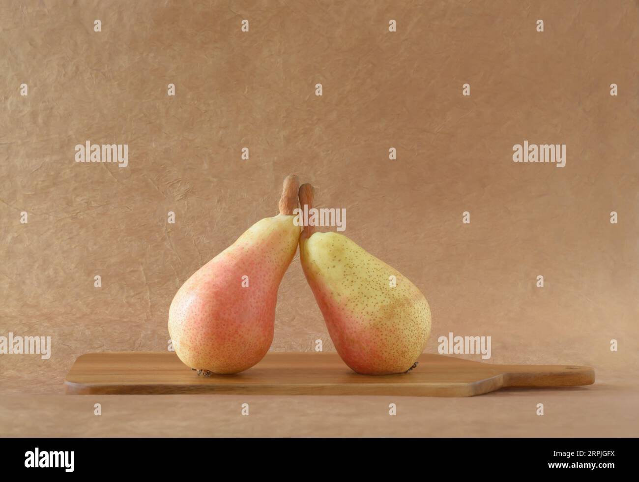 A pair of pears lying on a table on a beige-brown paper background in a ...