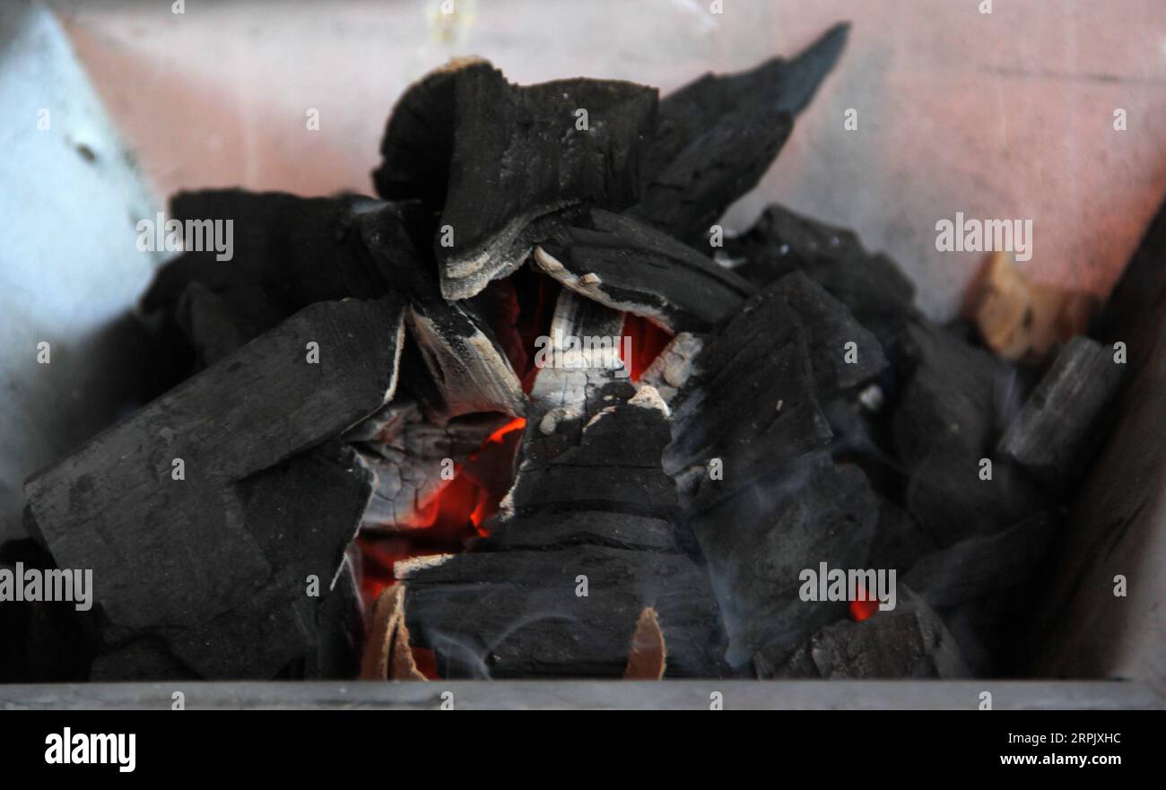 Chunks of charcoal on a grill stove starting to light a fire for ...