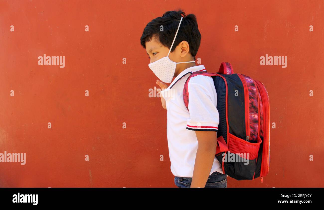 Latino boy with uniform shirt, backpack and mask back to school happy ...