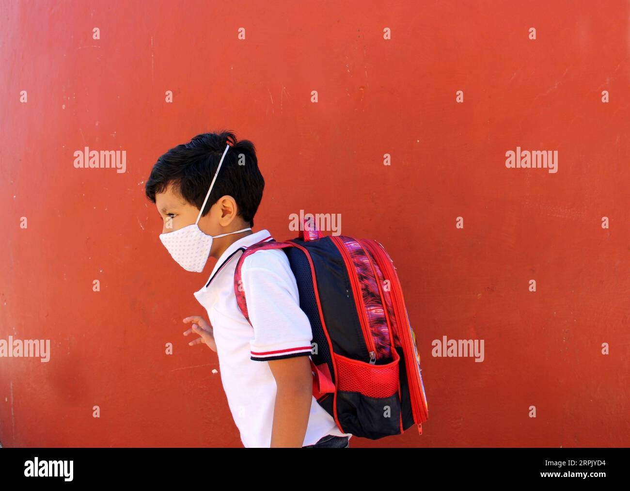 Latino boy with uniform shirt, backpack and mask back to school happy ...
