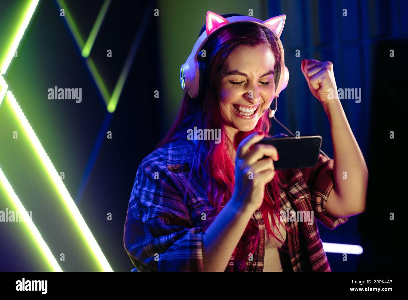 Happy female gamer celebrating winning a mobile game on a smartphone ...