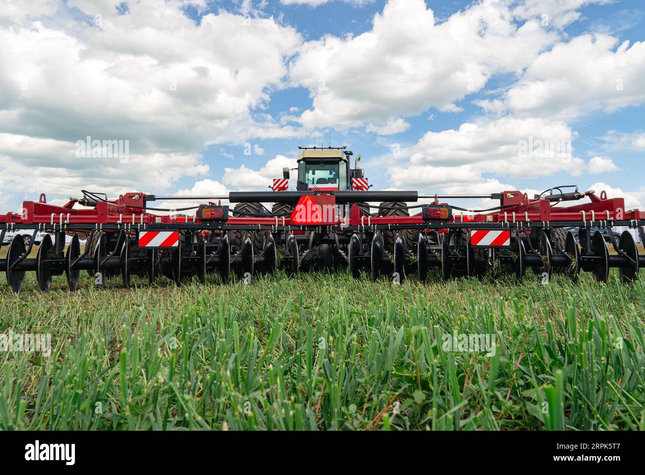a red tractor on a green field. Tillage for planting crops Stock Photo ...