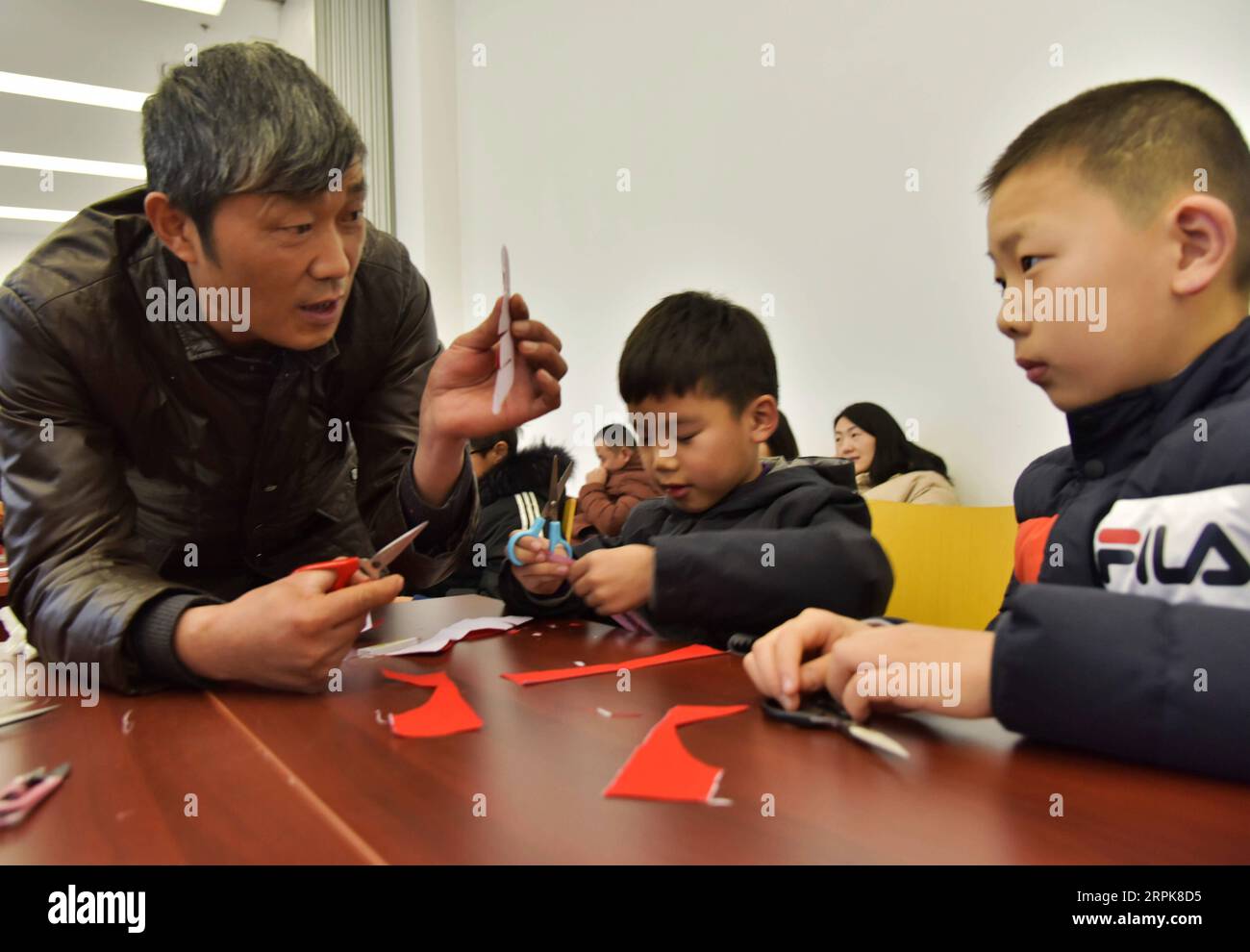 200102 -- NANTONG, Jan. 2, 2020 -- Paper-cutting artist Wang Zhujun teaches children paper ...