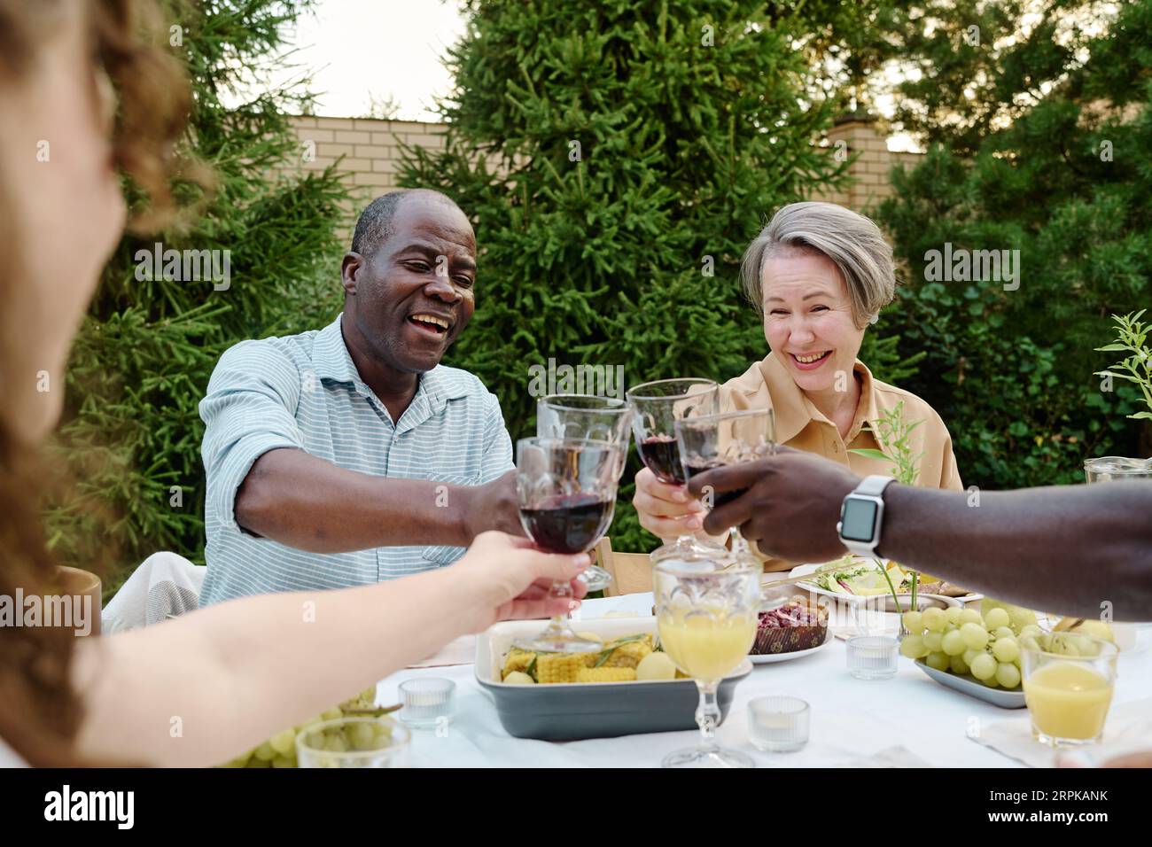 Happy mature intercultural couple with glasses of homemade red wine ...