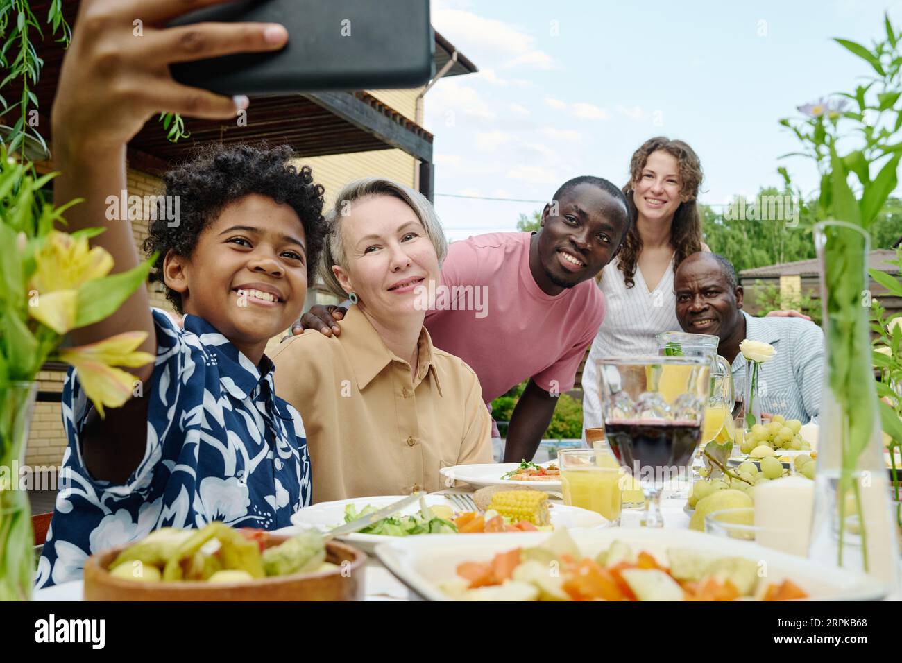 Happy large intercultural family looking at camera of smartphone held ...