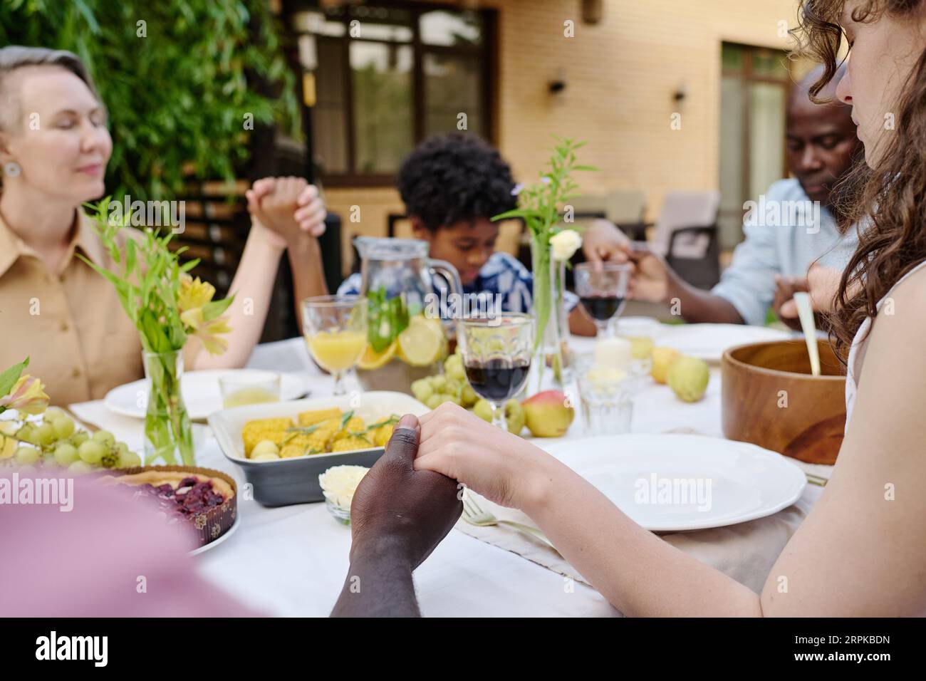 Focus on hands of young intercultural couple blessing food on served ...