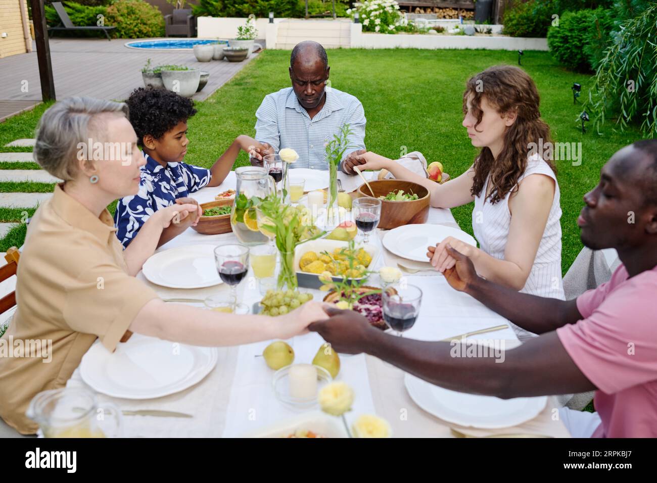 Large intercultural family of three generations holding by hands during ...