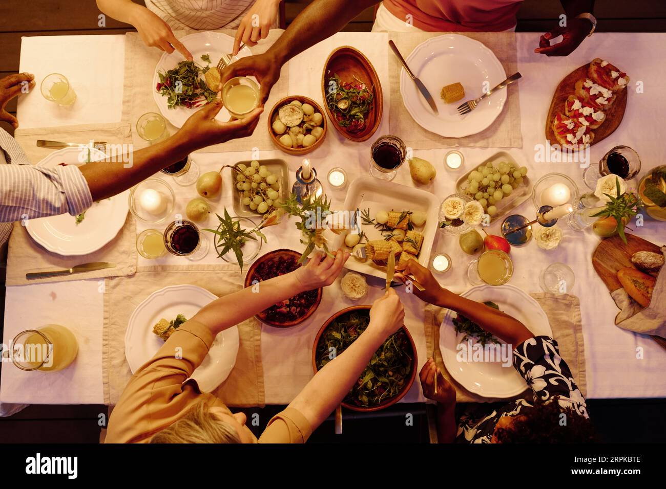 Top view of arms of intercultural family members sitting by served ...