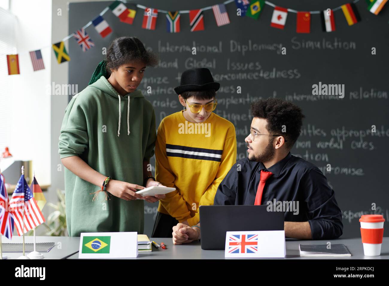 Students talking to teacher in the classroom after lesson, they ...