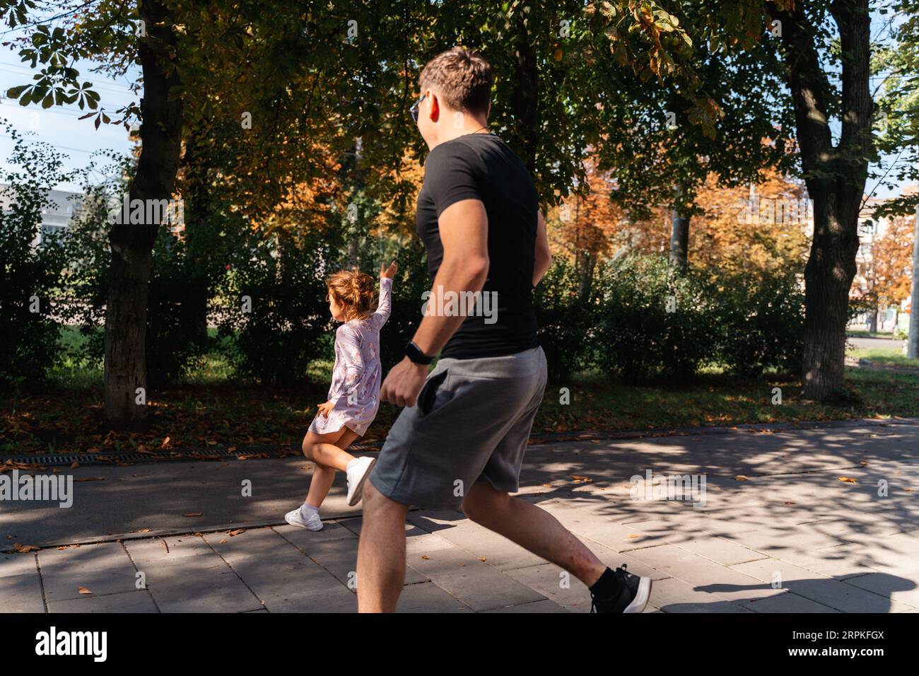 Father and child girl playing Tag chasing game outdoors on the streets ...