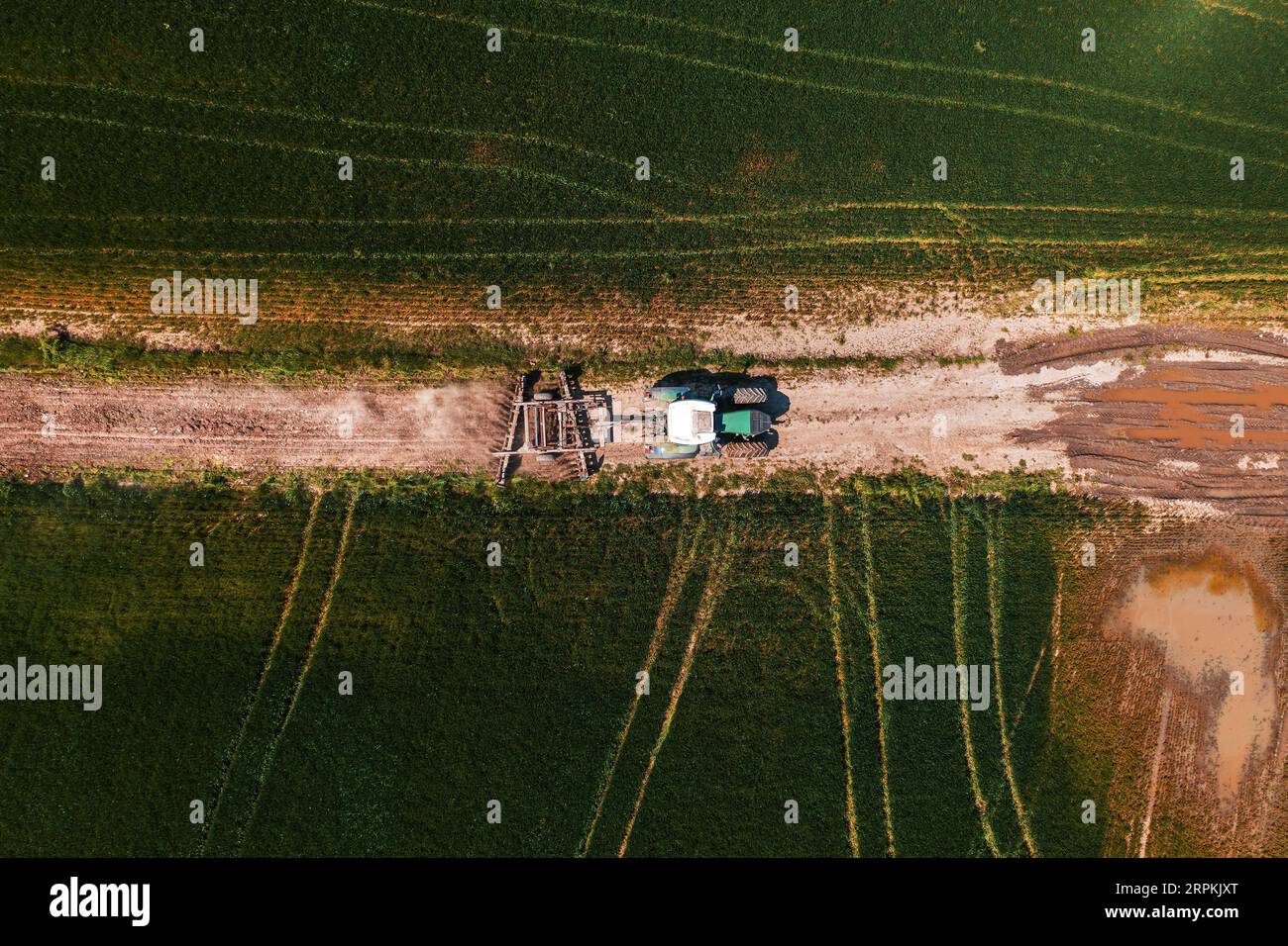 Aerial view of agricultural tractor with tiller attached on dirt road ...