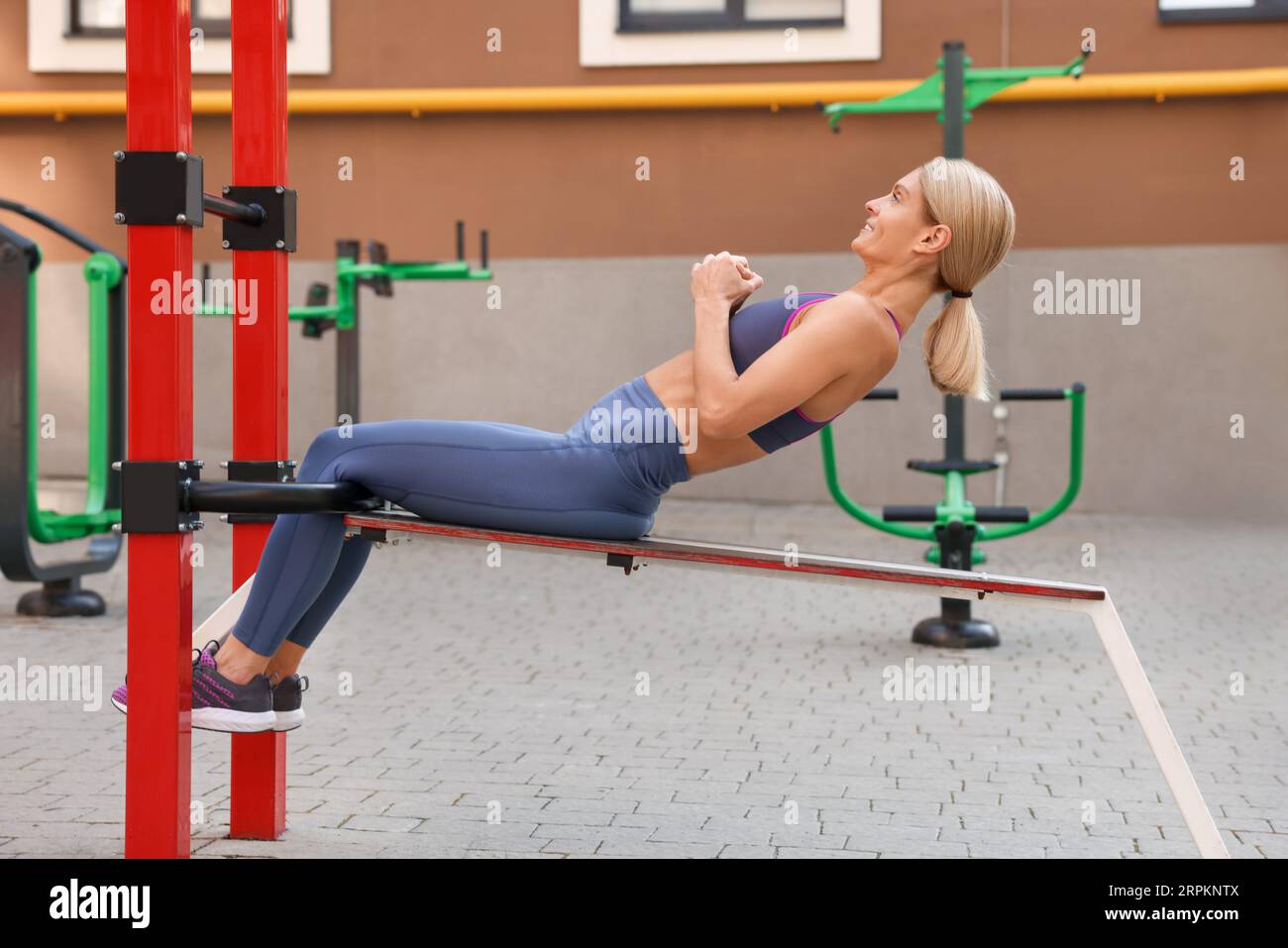 Woman doing abs exercise on bench at outdoor gym Stock Photo - Alamy
