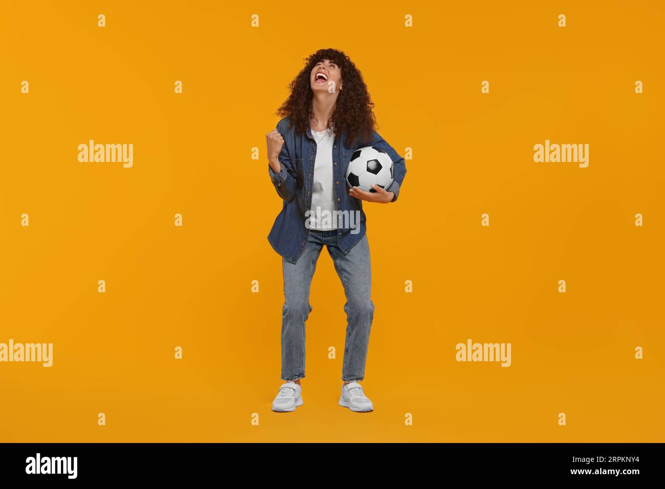 Happy fan with soccer ball celebrating on yellow background Stock Photo ...