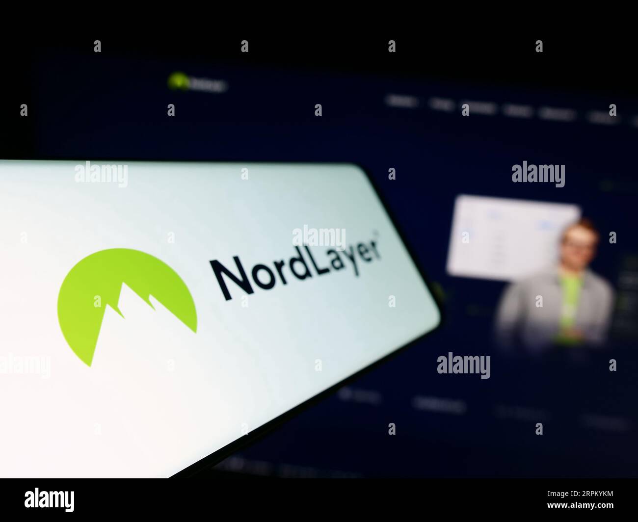 Smartphone with logo of network access security service NordLayer on screen in front of company ...