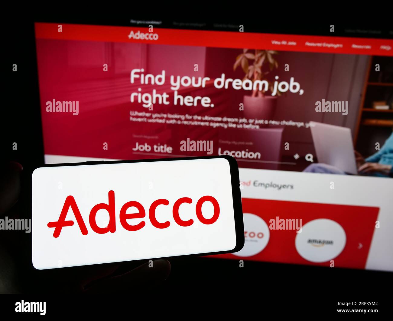 Person holding smartphone with logo of recruiting company Adecco on ...