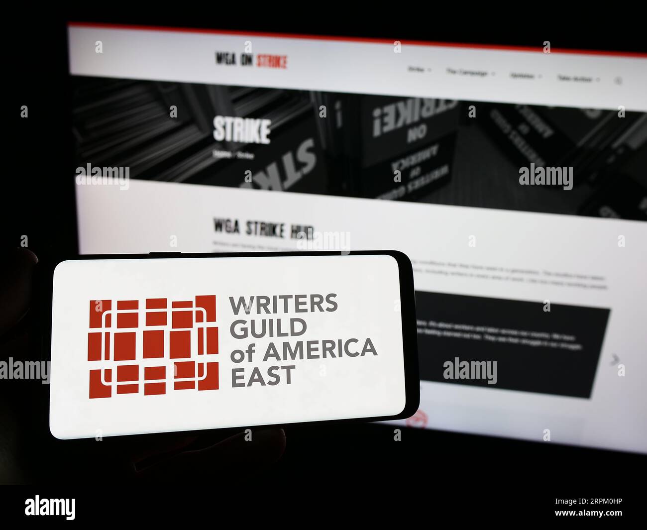 Person holding smartphone with logo of labor union Writers Guild of ...