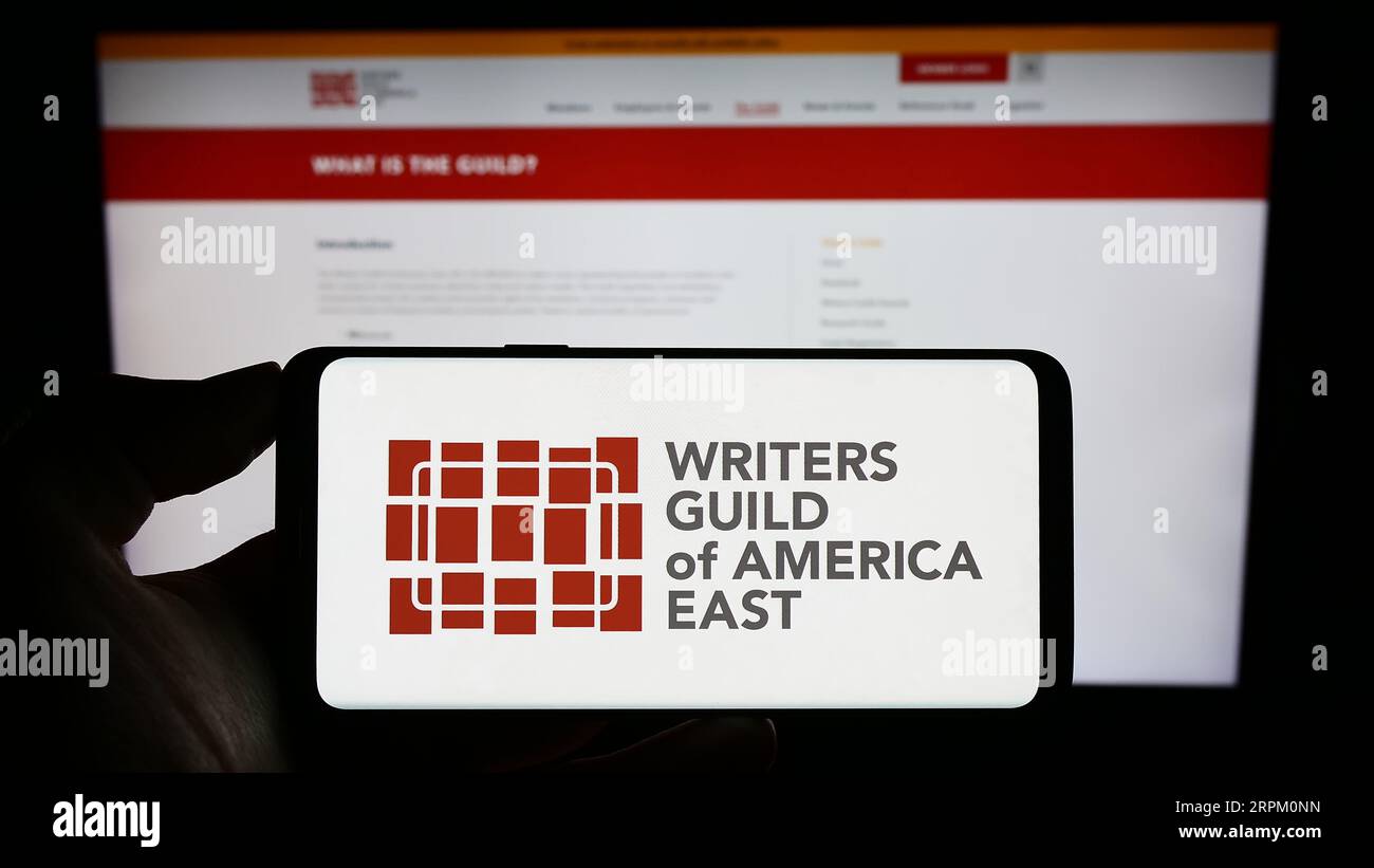 Person holding cellphone with logo of labor union Writers Guild of ...
