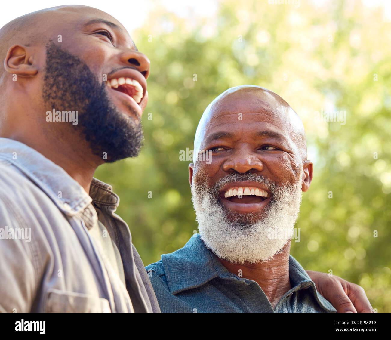 Portrait Of Laughing Senior Father With Adult Son Standing Outdoors In