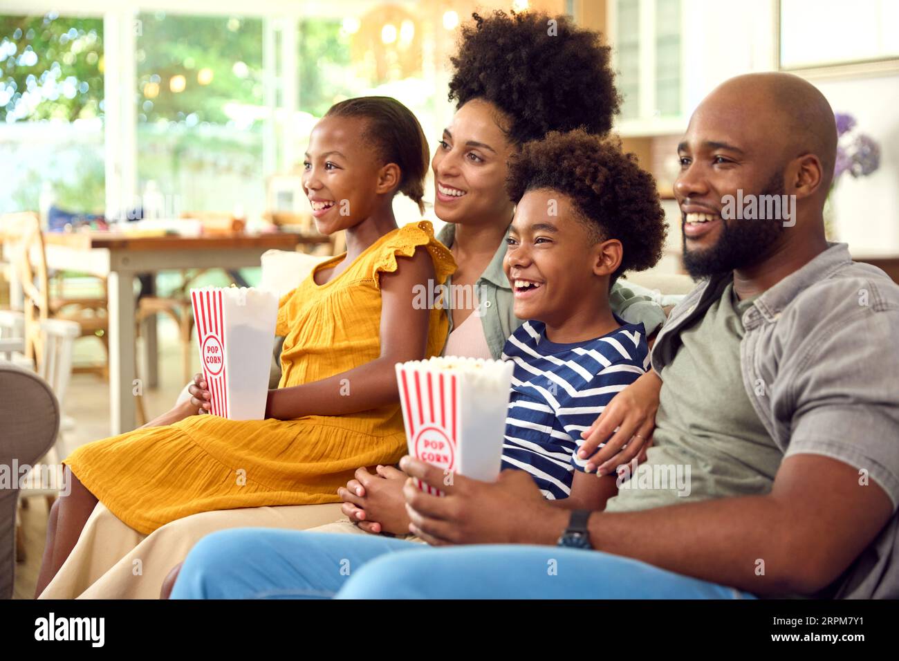 Family Eating Popcorn At Home Sitting On Sofa Together Streaming Show ...