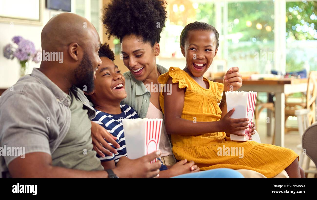 Family Eating Popcorn At Home Sitting On Sofa Together Streaming Show ...