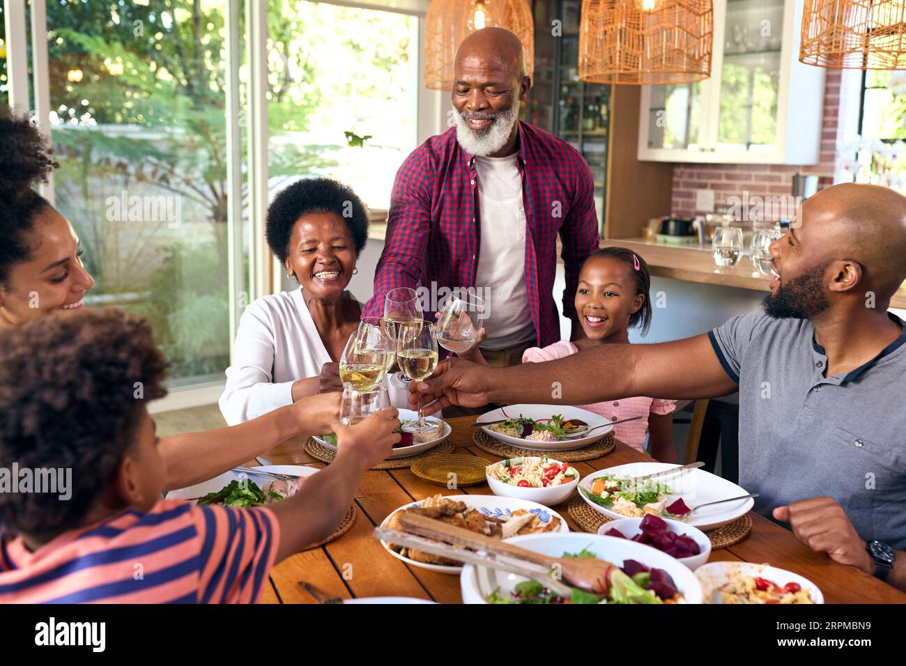 Multi-Generation Family Sitting Around Table Doing Cheers With Wine ...