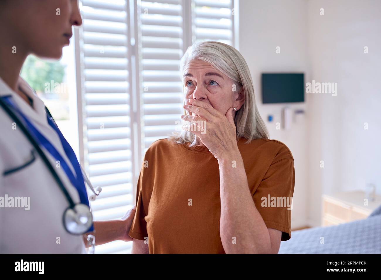 Female Nurse Wearing Uniform Giving Senior Woman Patient Bad News In ...