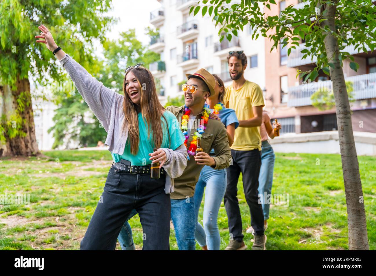 Group of multiethnic friends at birthday party in city park dancing ...