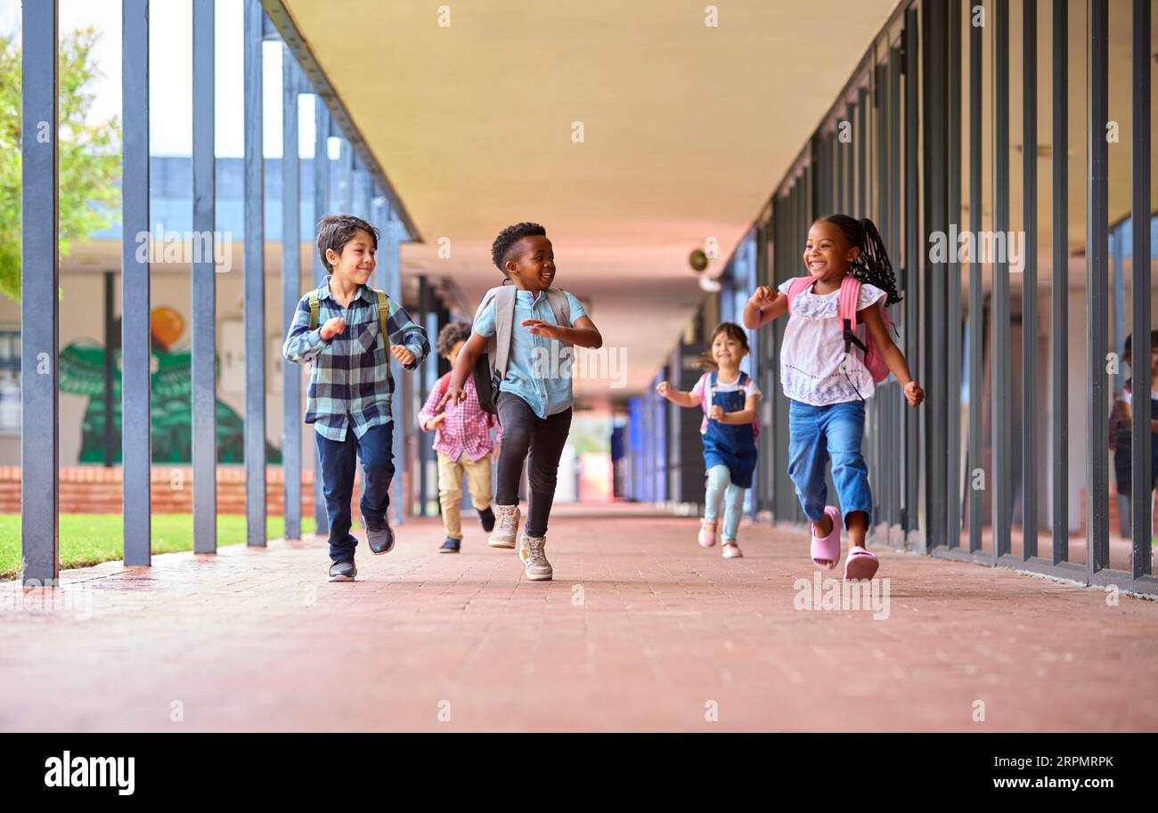Group Of Multi-Cultural Elementary School Pupils Running Along Walkway ...