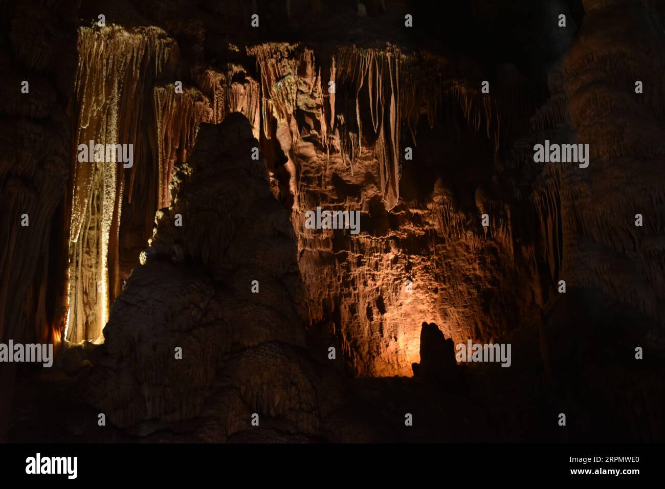 A majestic, dark cave illuminated by a single light source, casting a ...