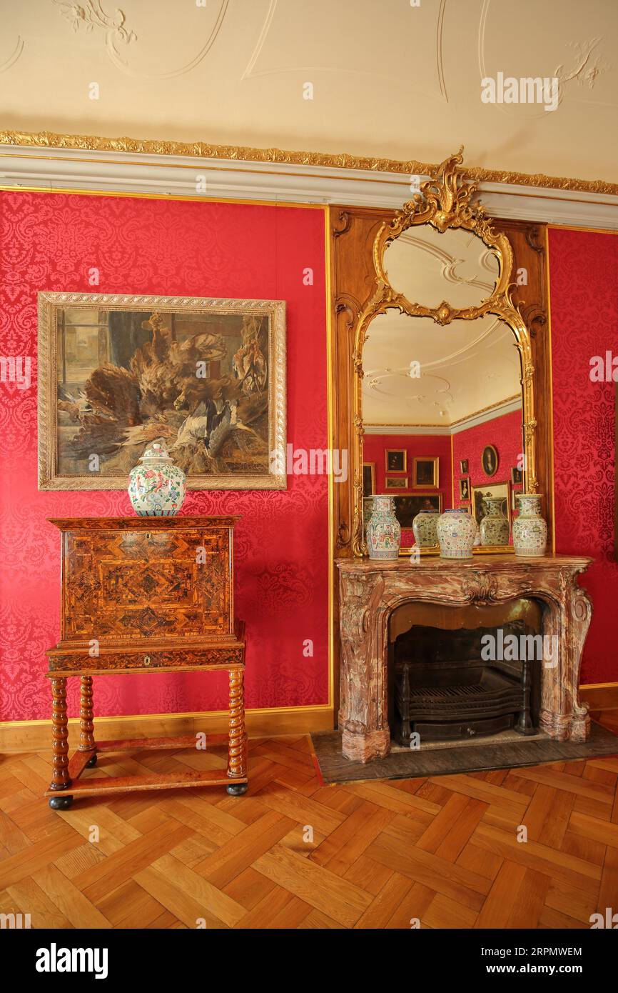 Red drawing room with chest of drawers, painting, wall mirror, parquet ...