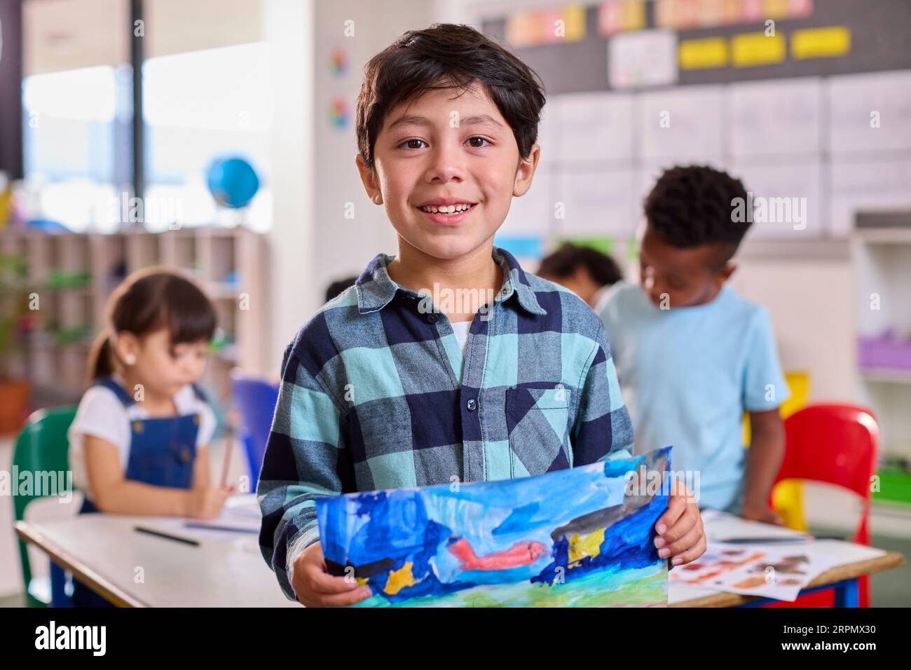 Classroom Portrait Of Proud Male Elementary School Pupil Holding ...