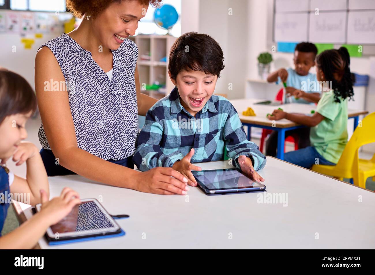 Female Teacher With Multi-Cultural Elementary School Pupils Using ...
