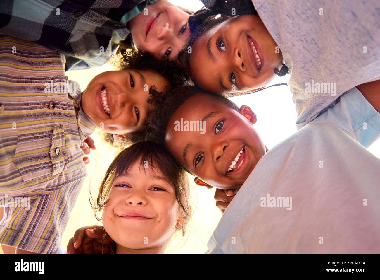 Low Angle Portrait Of Smiling Multi-Cultural Children Looking Down Into Camera Stock Photo - Alamy