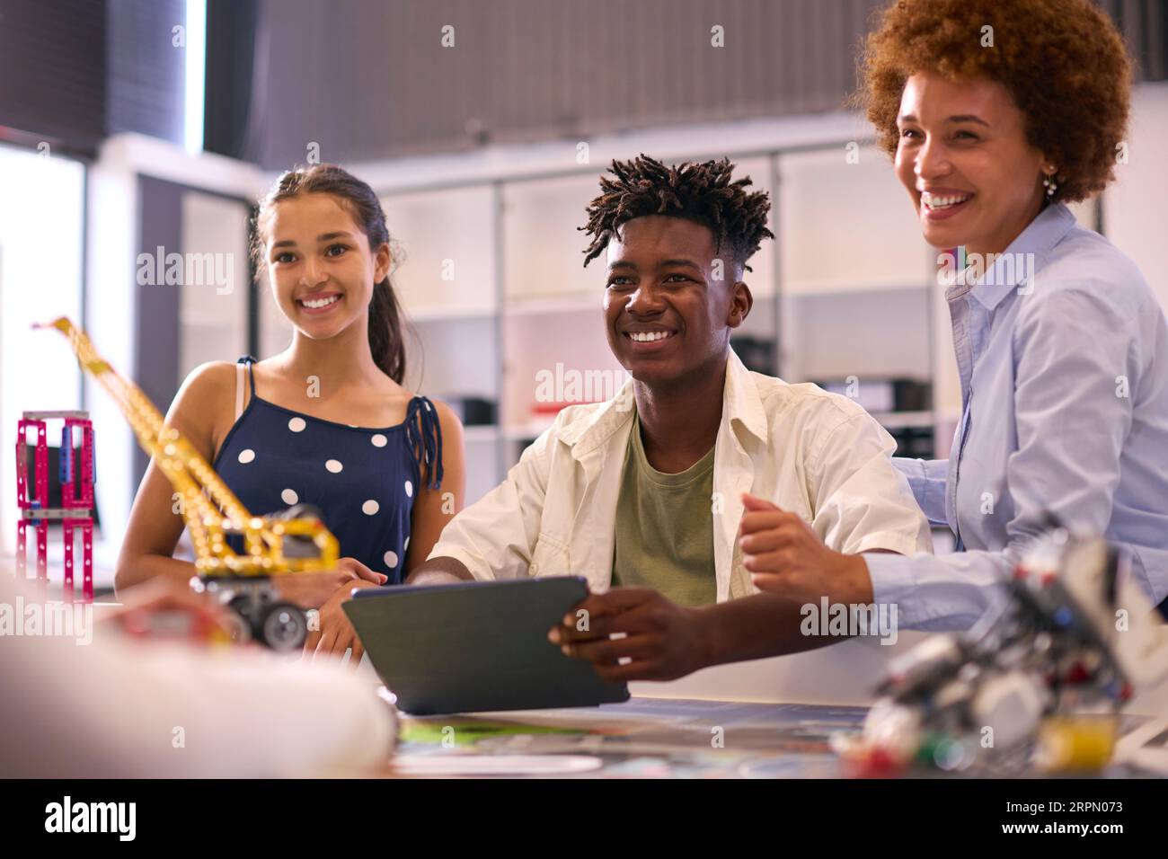 Female High School Teacher With Digital Tablet Helping Students In STEM ...