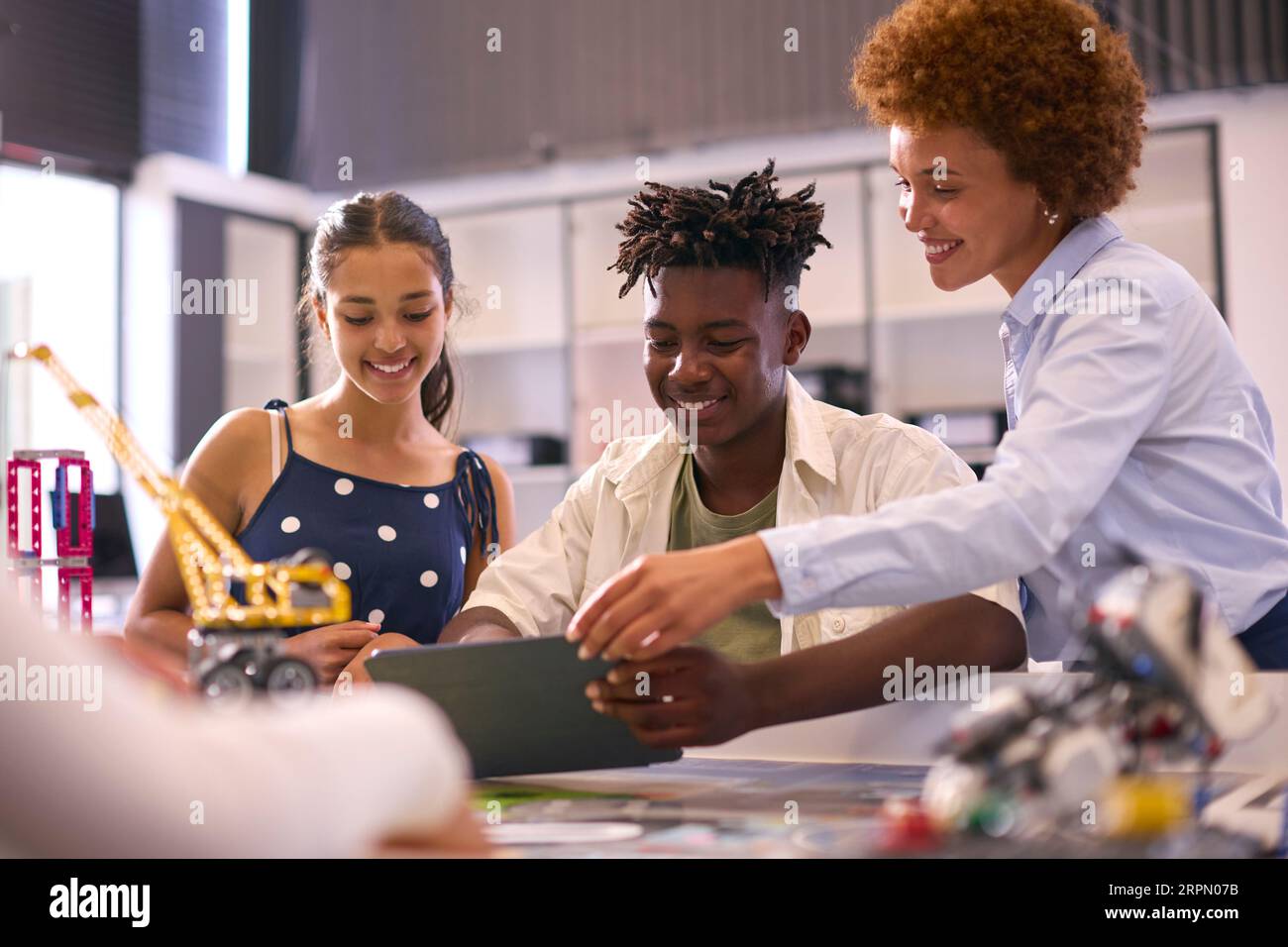 Female High School Teacher With Digital Tablet Helping Students In STEM ...